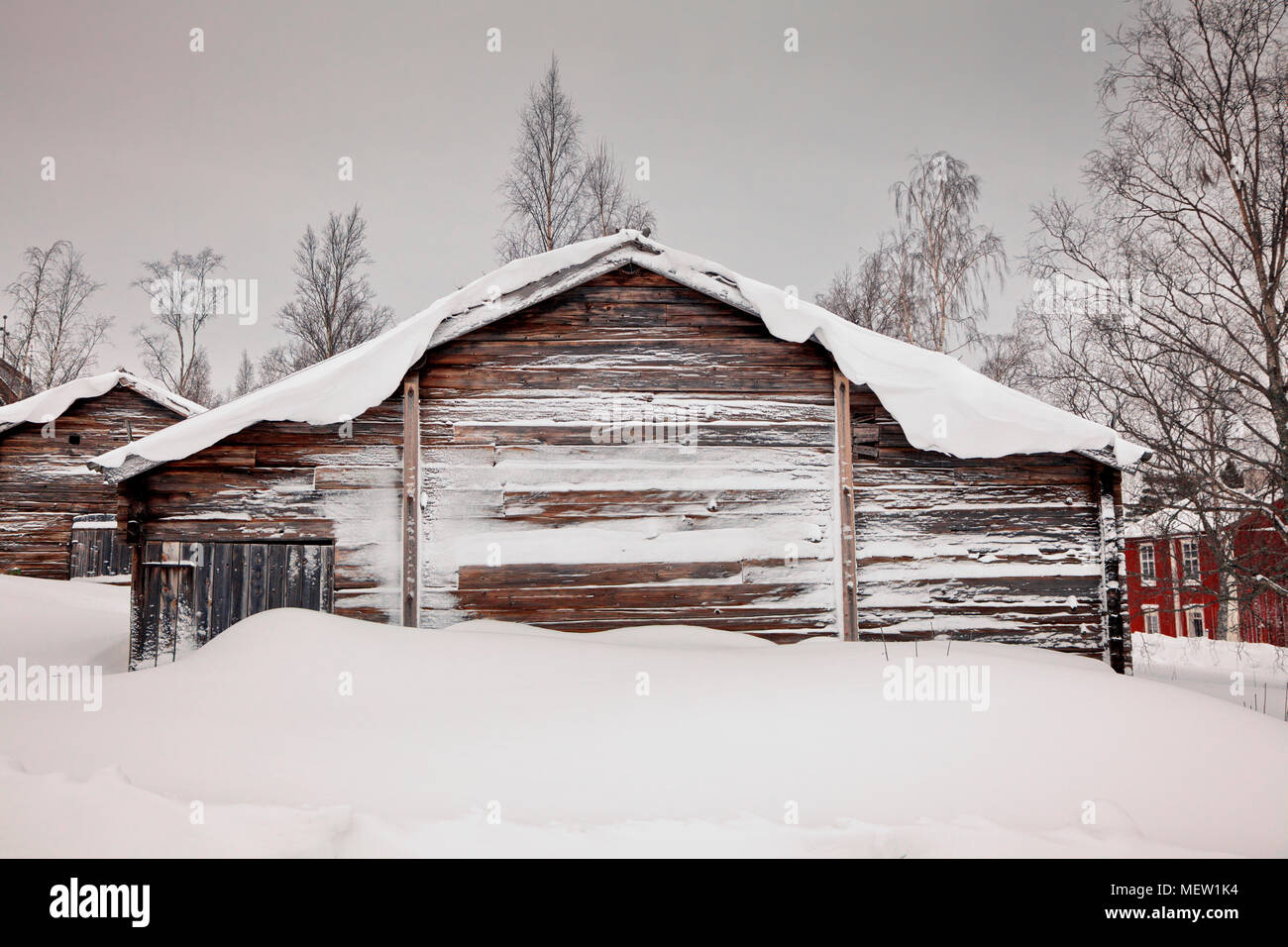 Old wooden farm buildings are covered with snow on a cold winter day ...