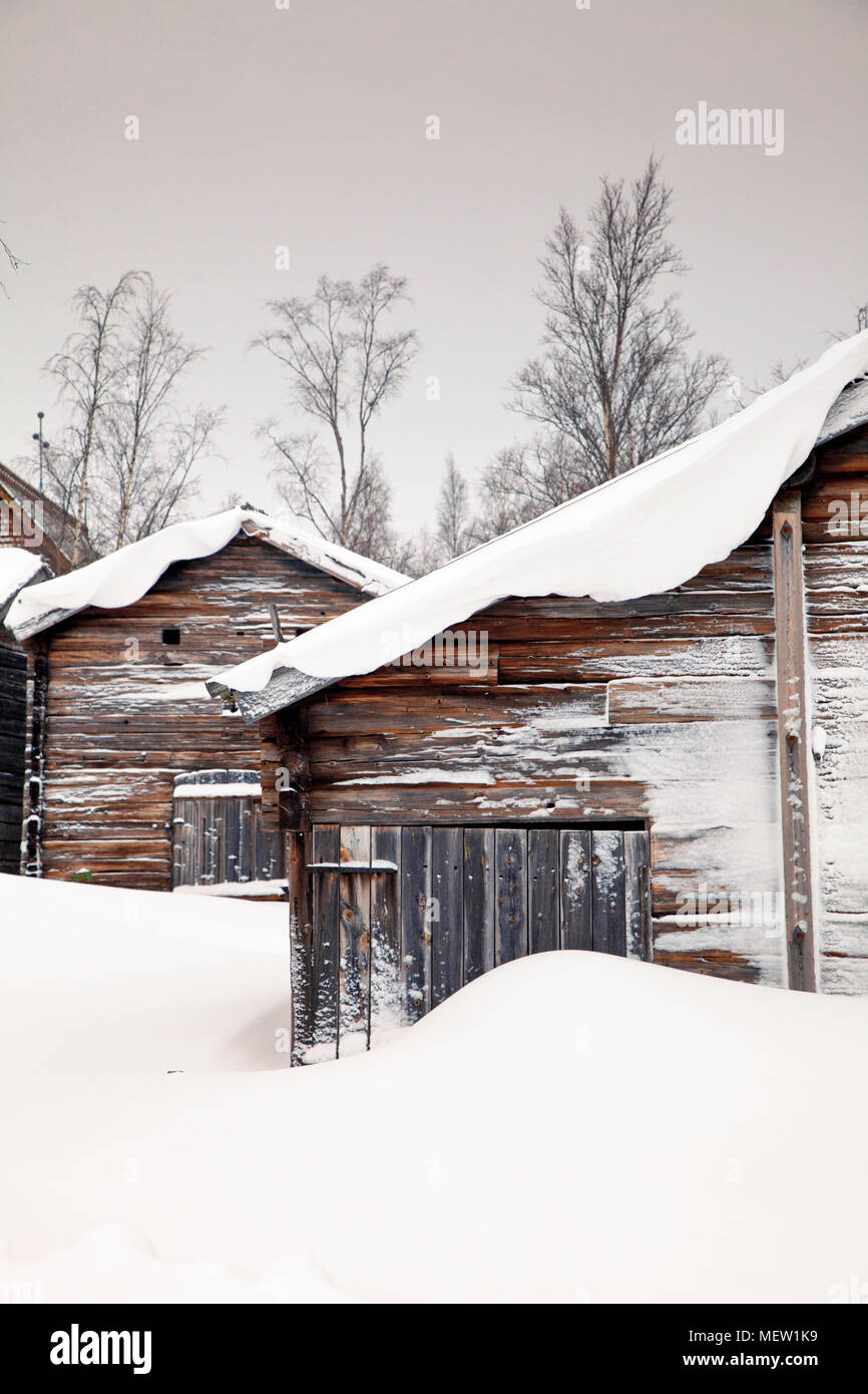 Old wooden farm buildings are covered with snow on a cold winter day ...