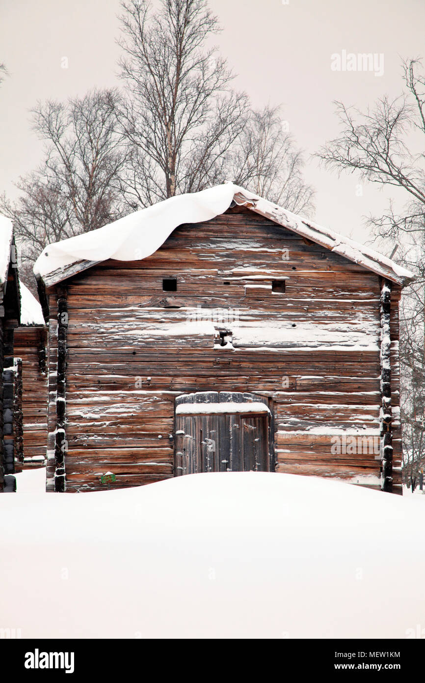 Old wooden farm buildings are covered with snow on a cold winter day ...