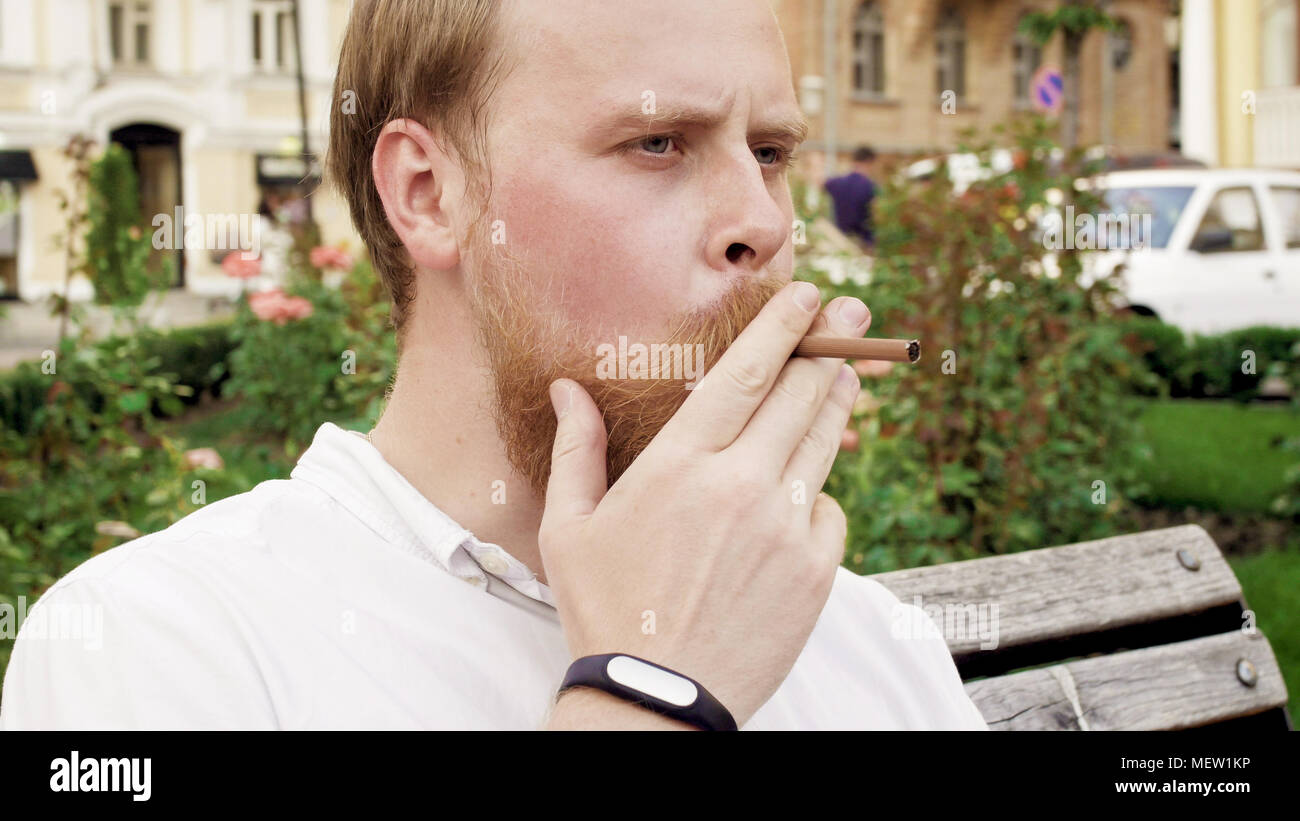 Closeup portrait of stylish hipster man smoking cigarette at park Stock ...