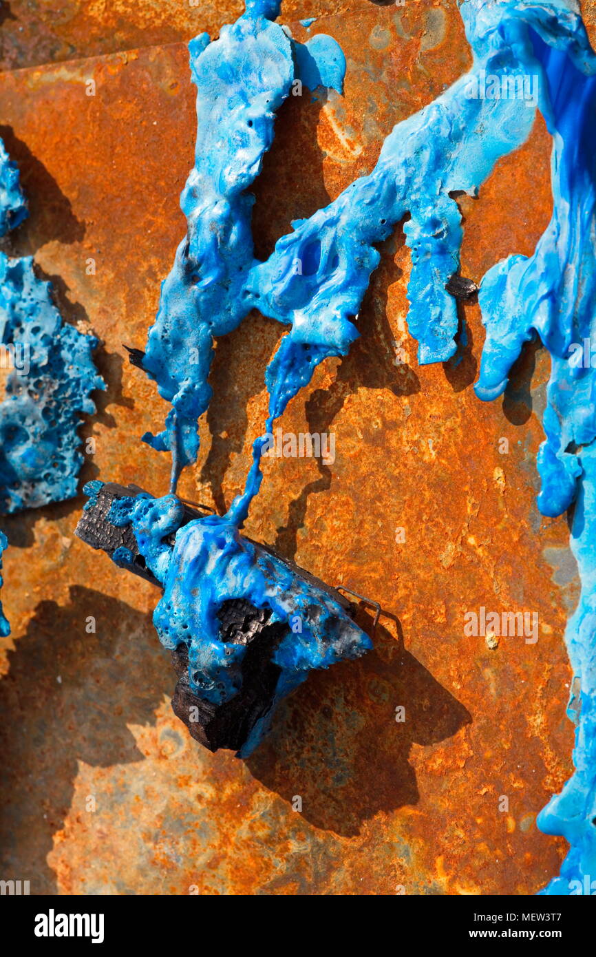 Blue melted plastic is covering rusty sheet metal on a burned up ...