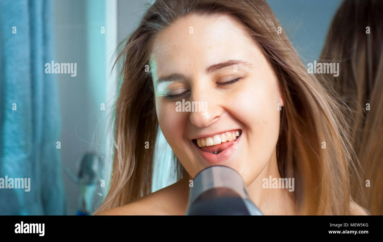 Happy smiling woman singing with hair dryer at bathroom Stock Photo - Alamy
