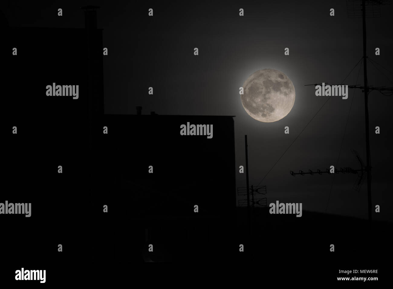 Full moon behind the buildings Stock Photo - Alamy