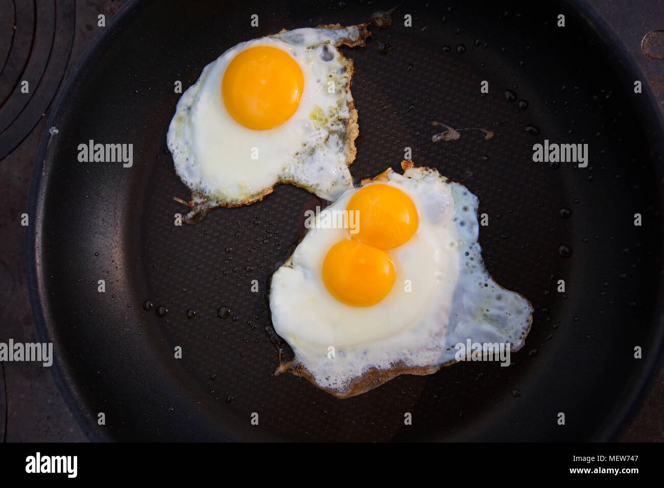 A double-yolked egg and a normal egg with one yolk are frying together ...