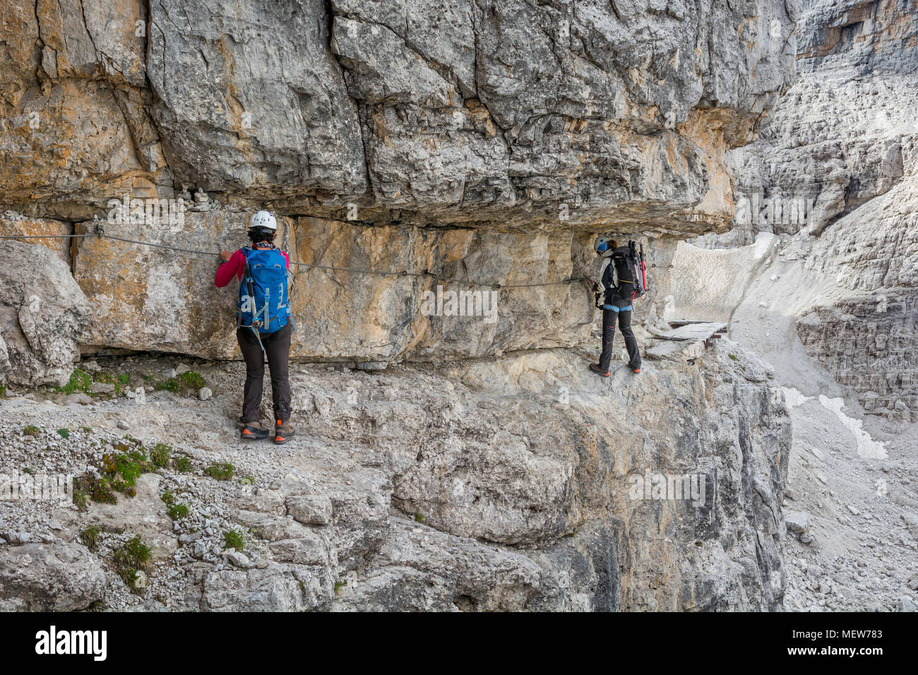 Climbers walking on narrow ledge protected by via ferrata set Stock ...