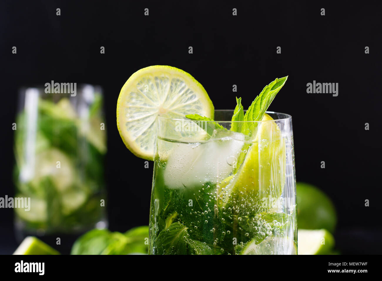 Mojito cocktail with with garnish in glass on black table. Low key ...