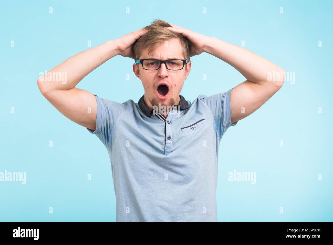 Shocked or surprised young man on blue background Stock Photo - Alamy
