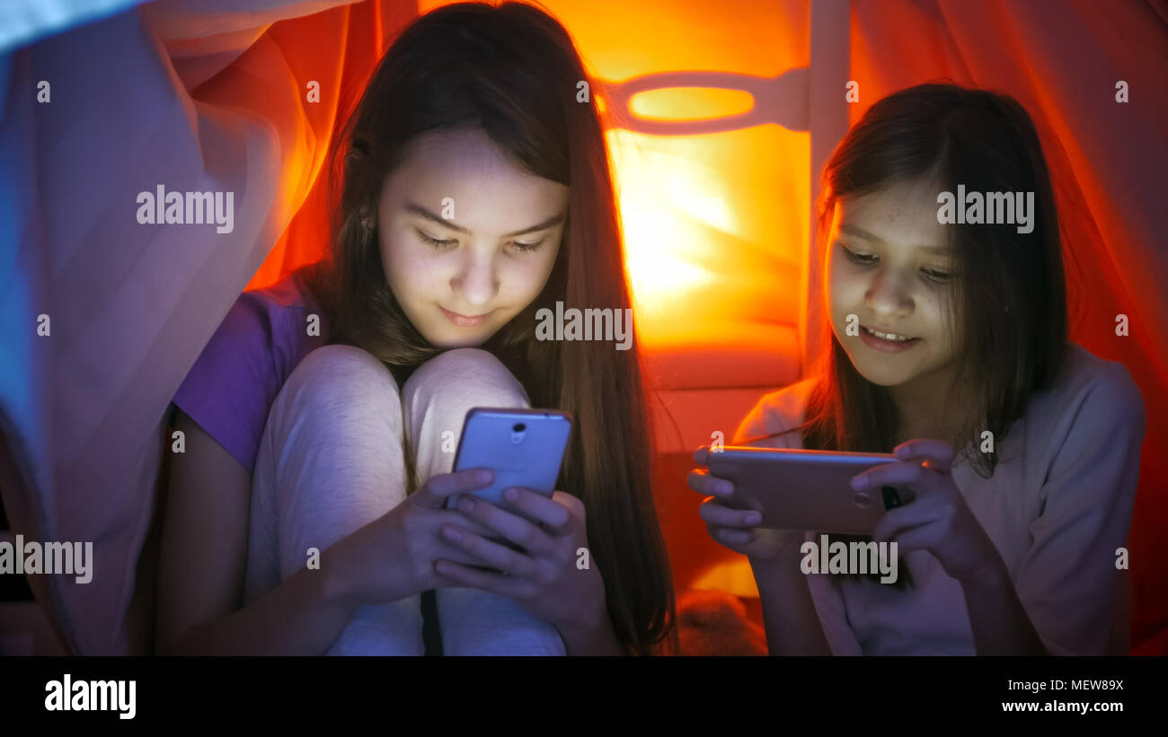Portrait of two teenage girls typing message in social media on mobile ...