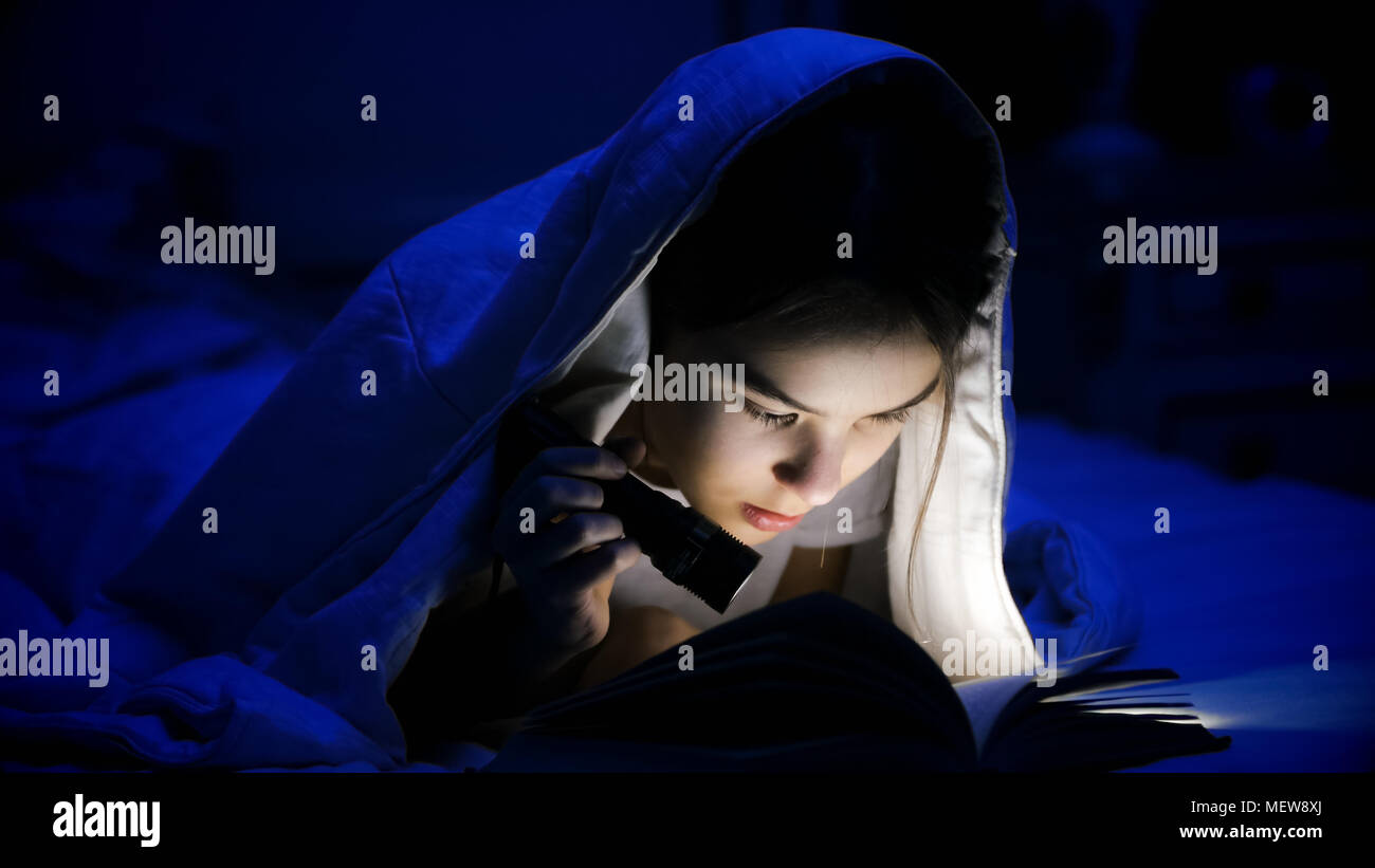 Portrait of girl with flashlight reading scary book at night Stock ...