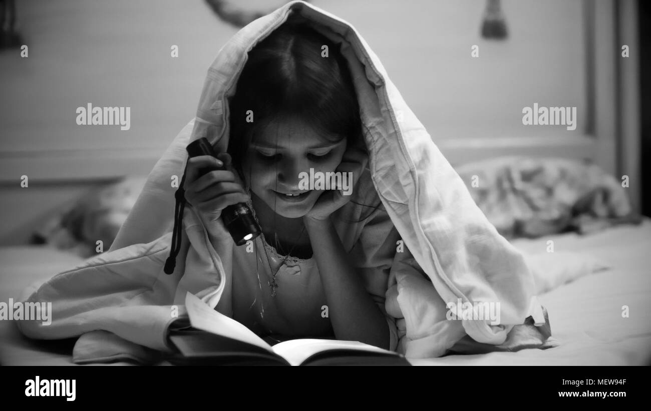 Black and white portrait of smiling teenage girl with torch reading ...