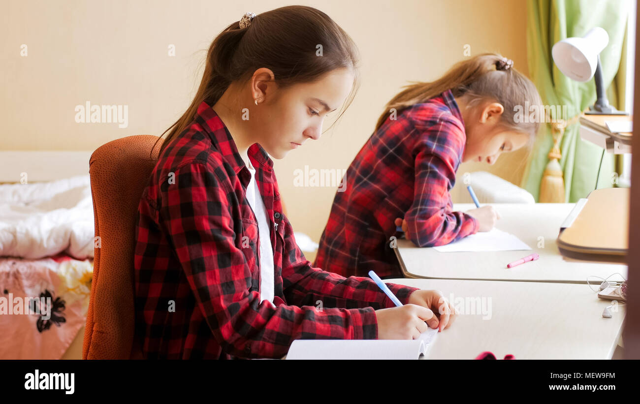 Two teenage girls doing homework in bedroom behind desk Stock Photo - Alamy