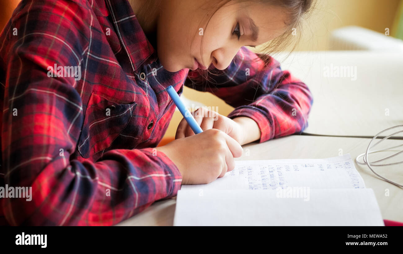 Closeup portrait of concentrated girl writing task with pen in copybook ...