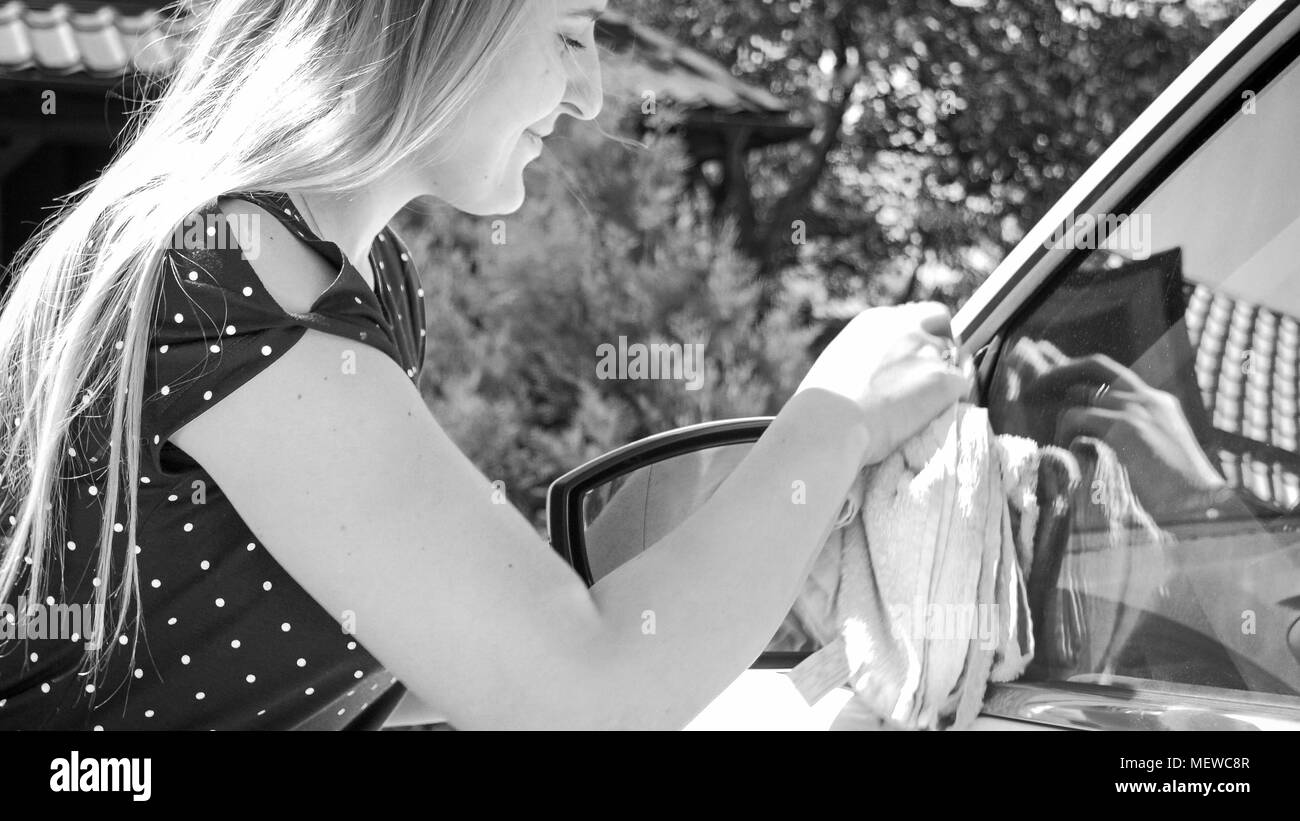 Black and white photo of smiling young woman polishing and wiping car ...