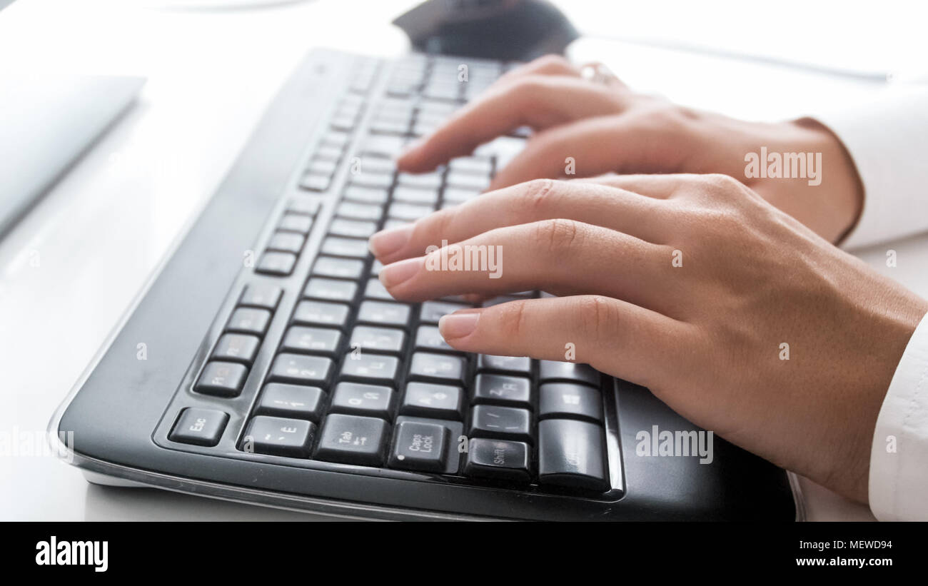Closeup photo of female hands typing text on black keyboard at office ...