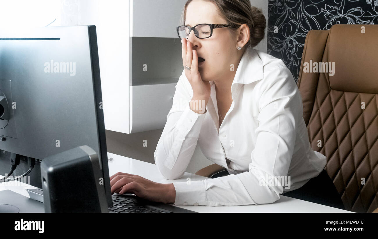 Beautiful female boss yawning while working in office Stock Photo - Alamy