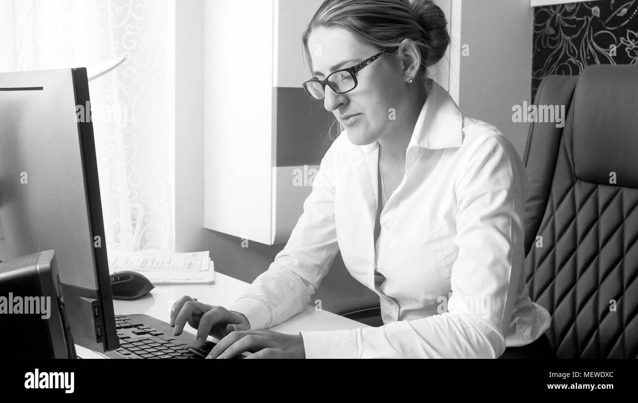 Black and white portrait of young secretary working on computer at ...