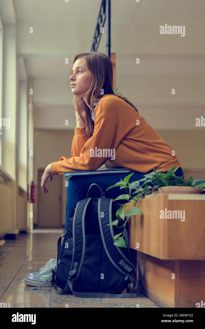 Young depressed lonely female college student sitting in the hallway at ...