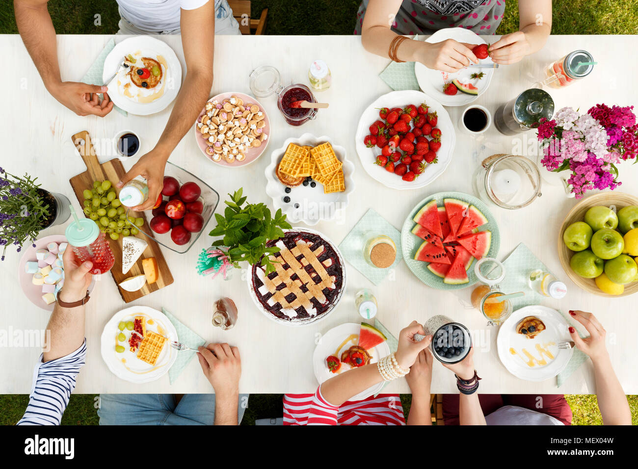 Group of friends sharing meal outdoors drinking coffee and eating ...