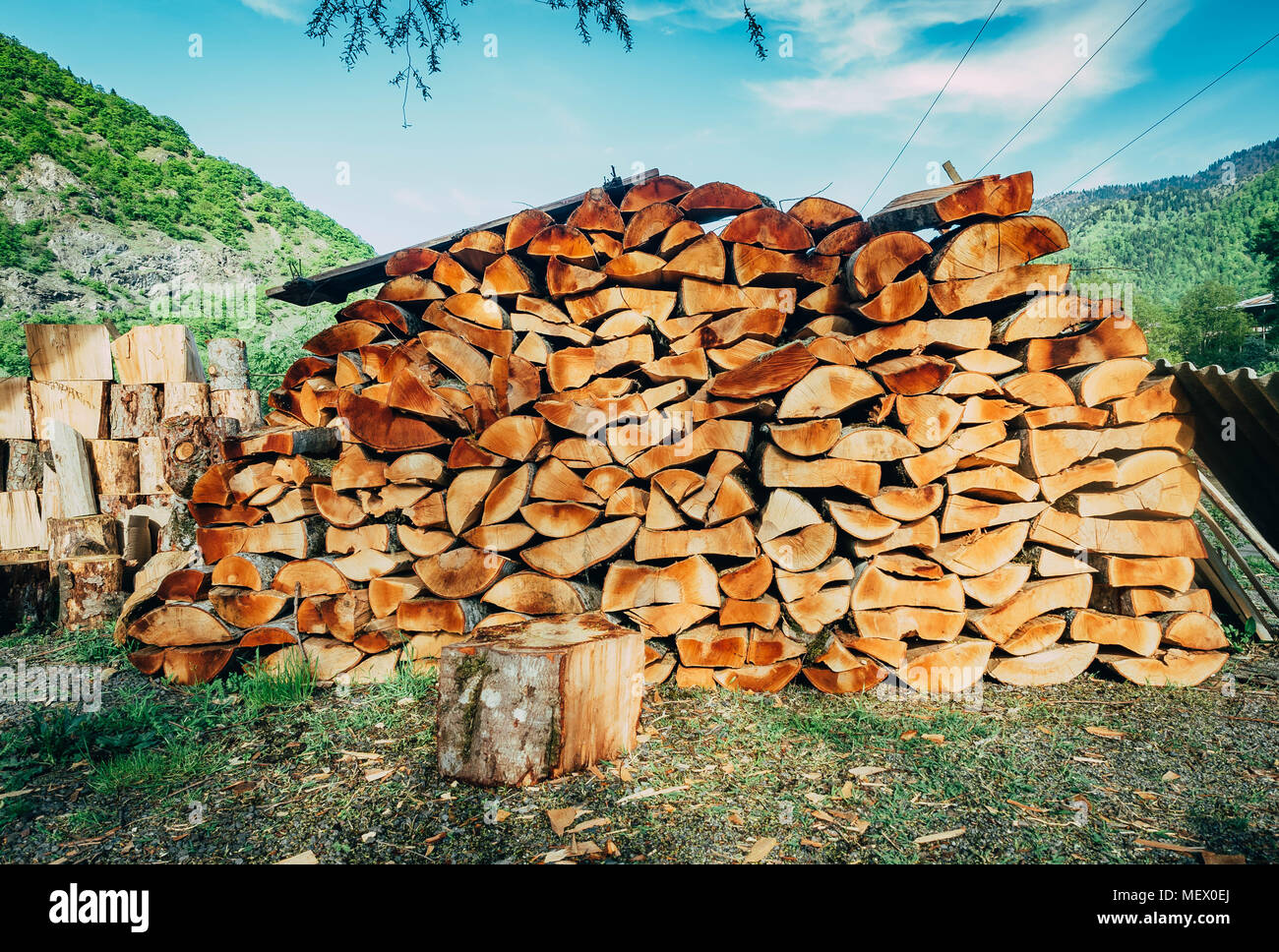 The chopped wood is packed in a woodpile outdoor. Firewood stacked on ...