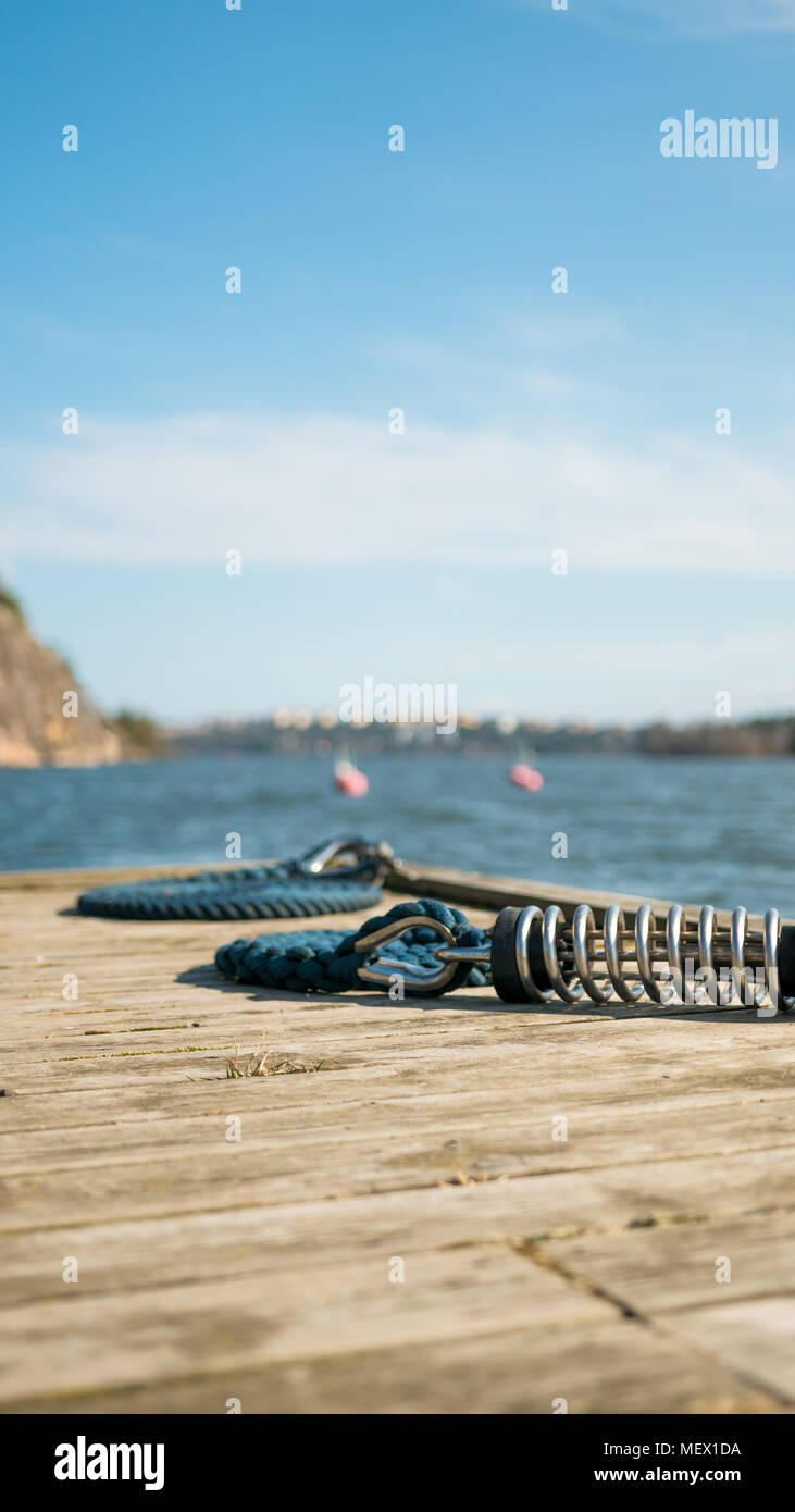 Coastal dock on a rocky area with blue nautical sailing rope for boats ...