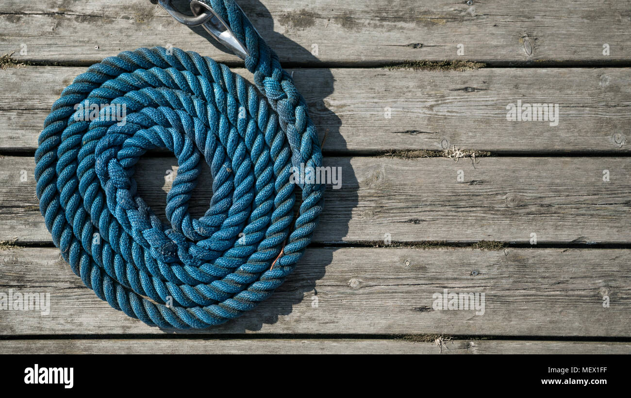 Coastal dock on a rocky area with blue nautical sailing rope for boats ...