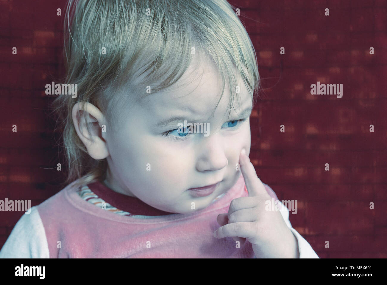 blonde child with blue eyes reflects in a pensive posture Stock Photo ...