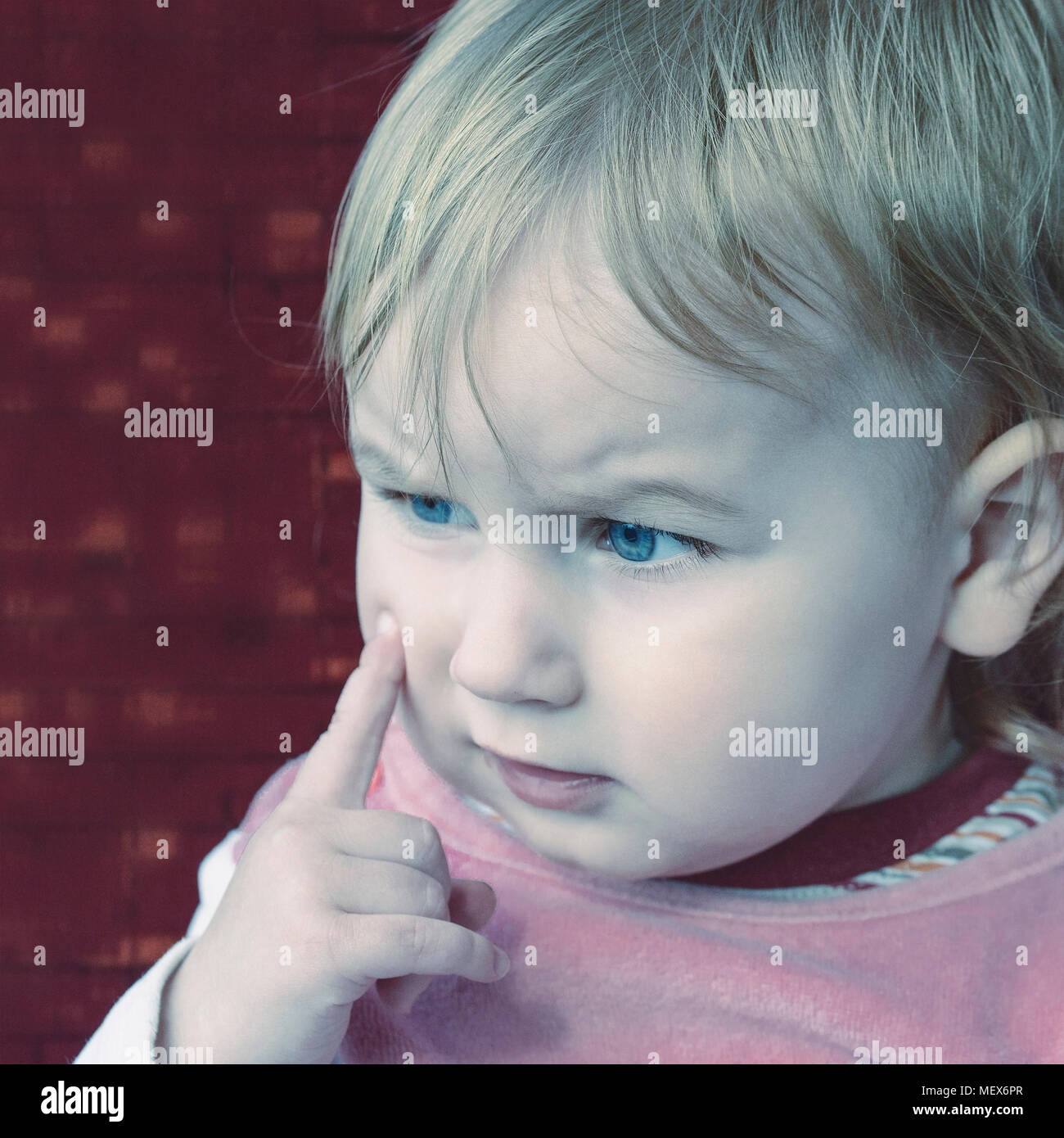blonde child with blue eyes reflects in a pensive posture Stock Photo ...