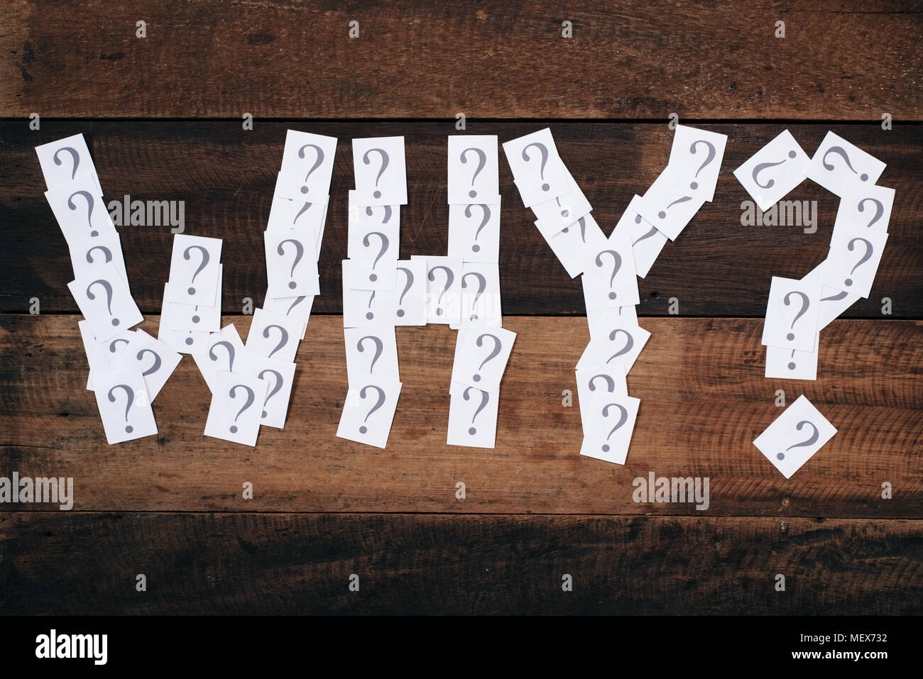 white paper note with question mark arranged to make a WHY word on ...