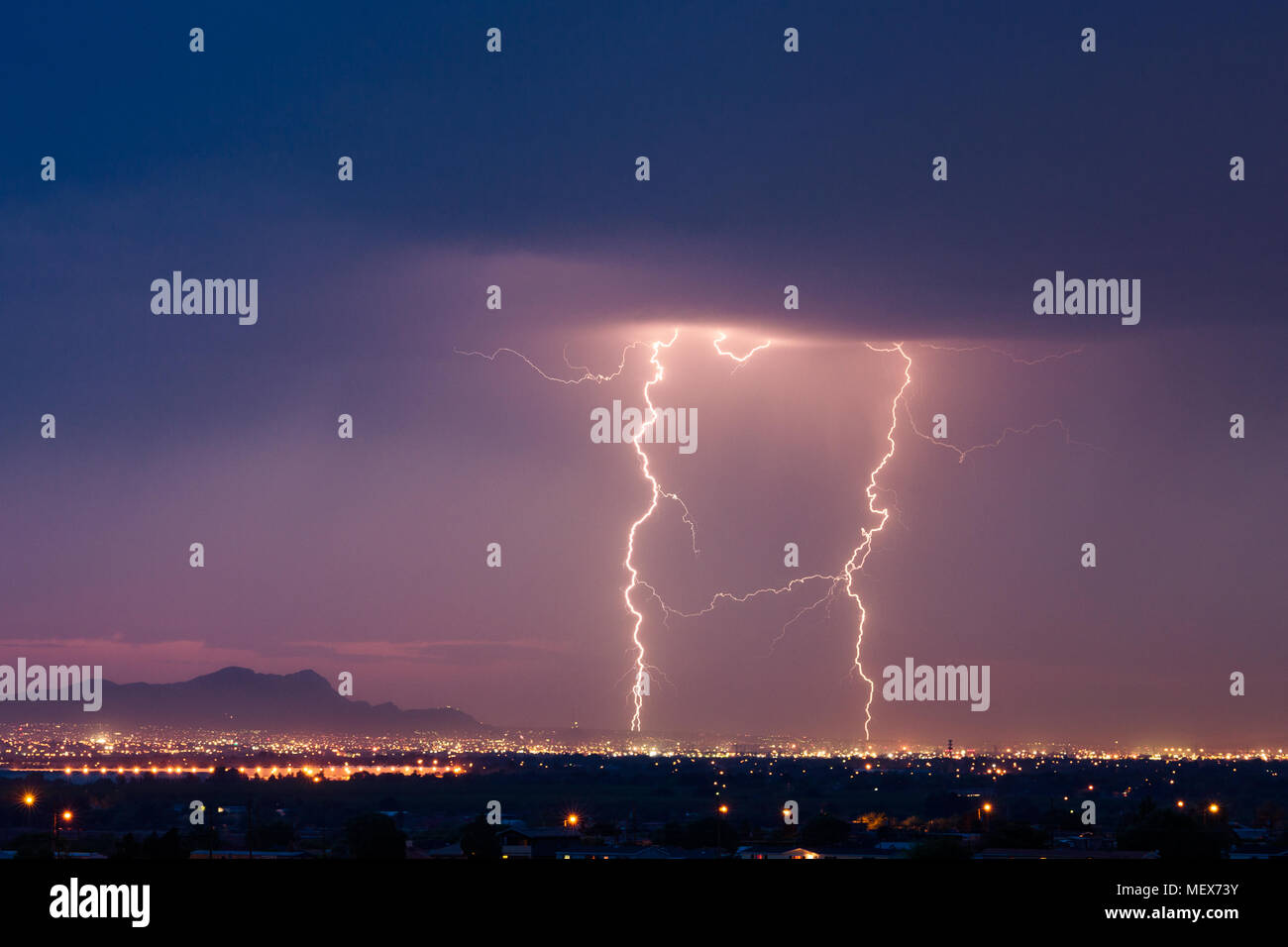 A pair of dramatic cloud to ground lightning bolts strike the city and ...