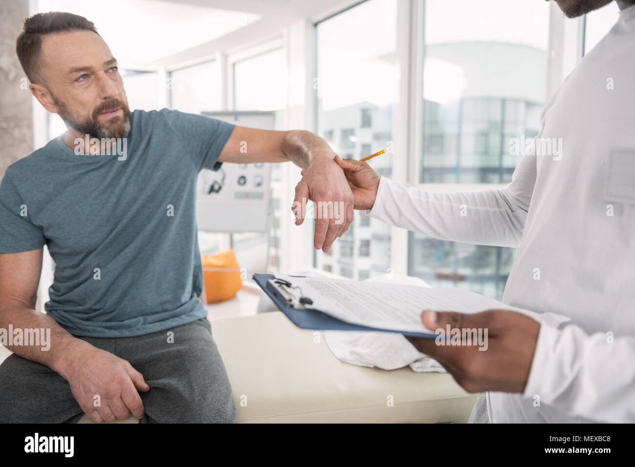 Nice handsome man showing his arm to the doctor Stock Photo - Alamy