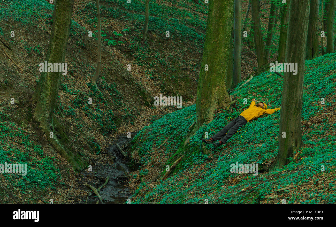 man wearing yellow jacket laying down on the ground in a fresh spring ...
