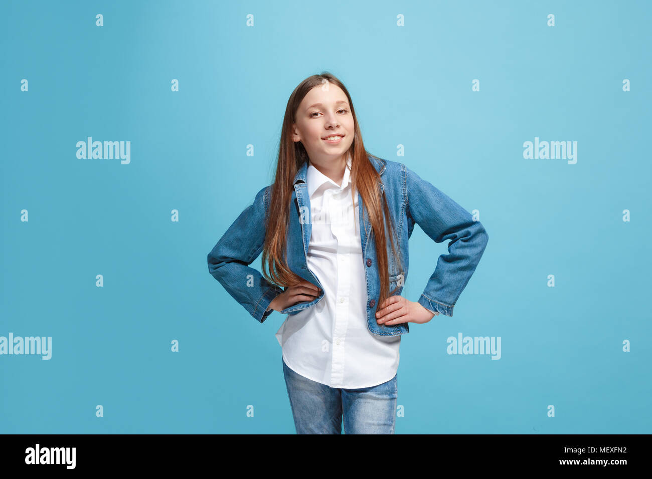 The happy teen girl standing and smiling against blue background Stock ...