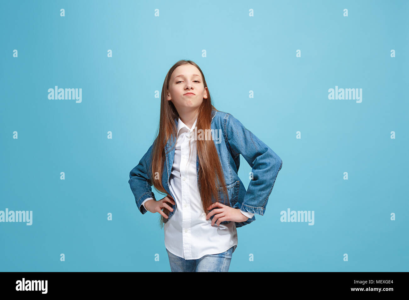 The happy teen girl standing and smiling against blue background Stock ...