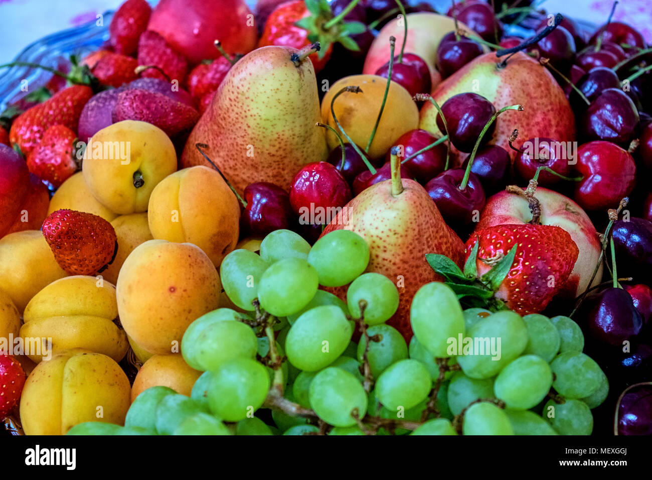 A lot of fruits and berries lying on the table apples, grapes, apricots ...