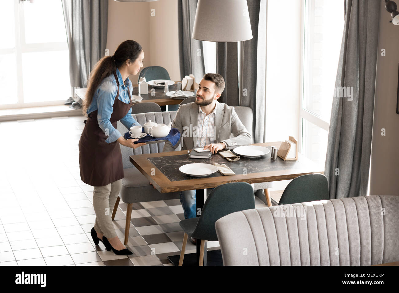 Friendly waitress giving tea to customer Stock Photo - Alamy