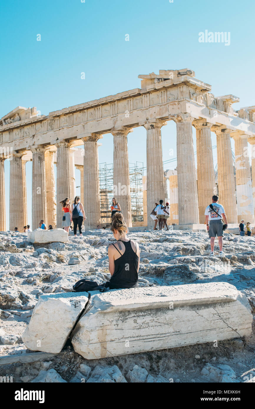 A girl sitting in front of the ancient temple of Parthenon, Acropolis, UNESCO World Heritage ...