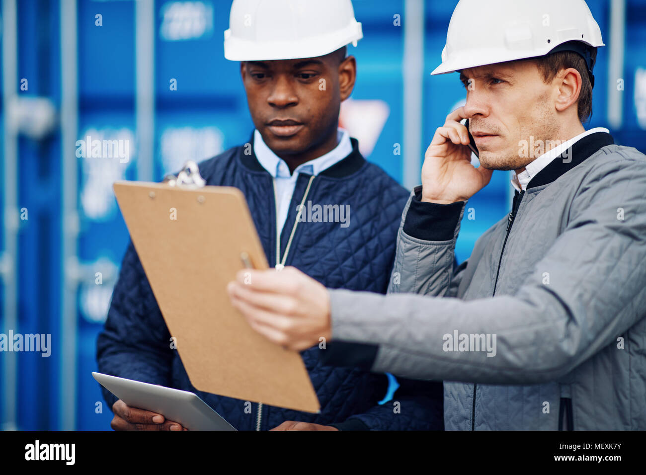 Freight manager talking on a cellphone and reading an inventory list on ...
