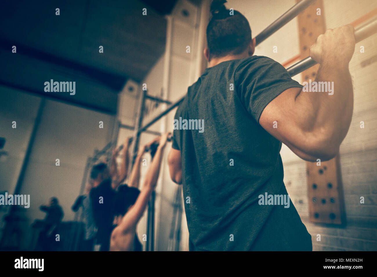Group of fit people doing pull ups together during an exercise class at ...