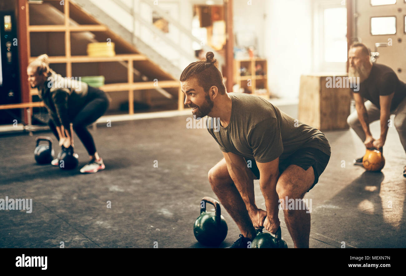 Fit and focused group of people in sportswear lifting dumbbells ...