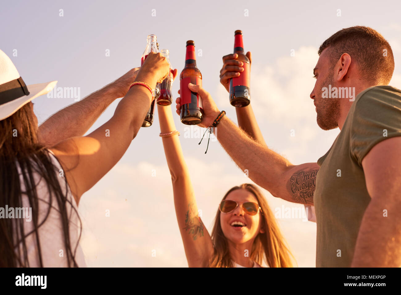 Cheerful friends raising bottles beer hi-res stock photography and ...