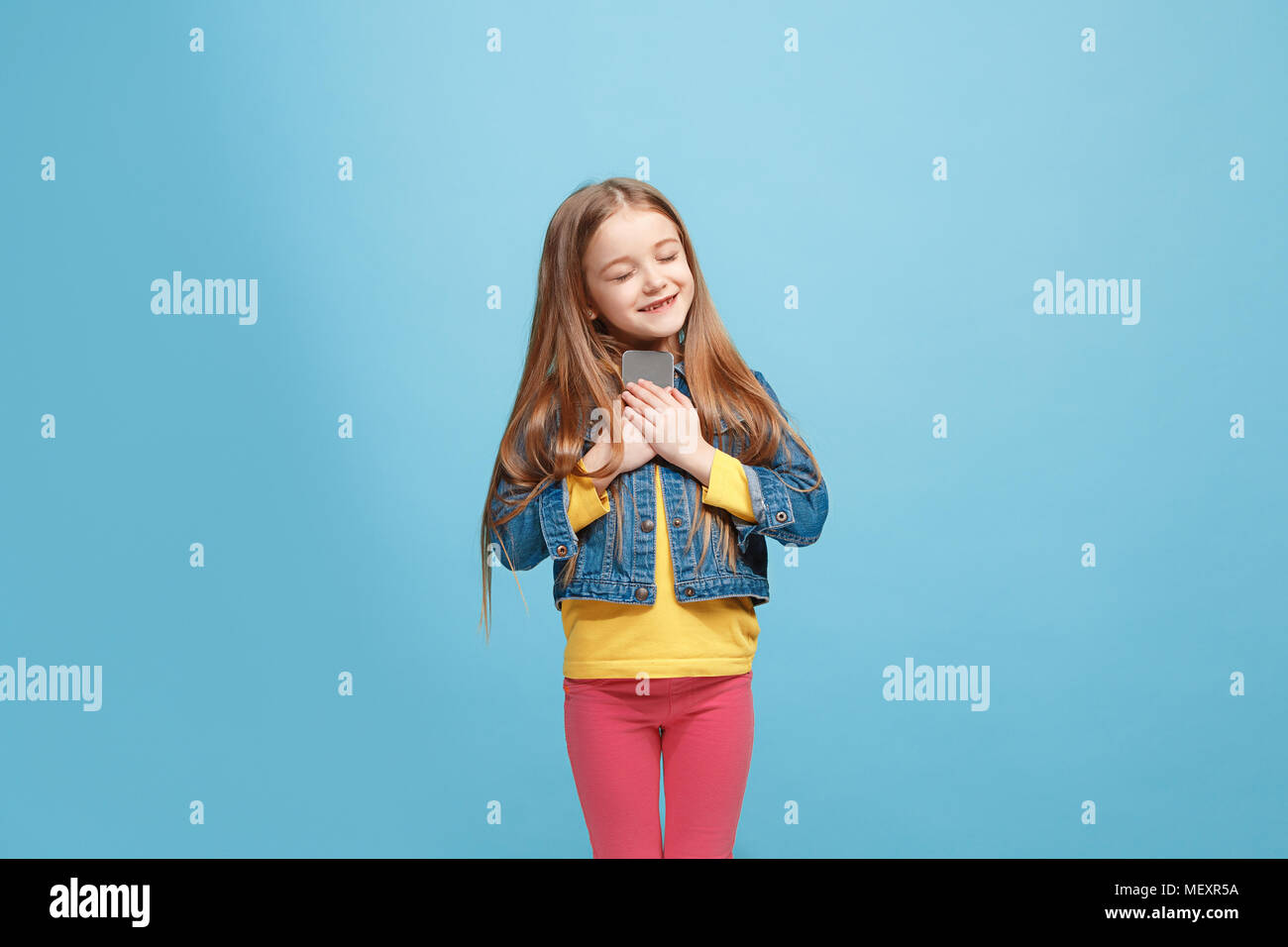 The happy teen girl standing and smiling against blue background Stock ...