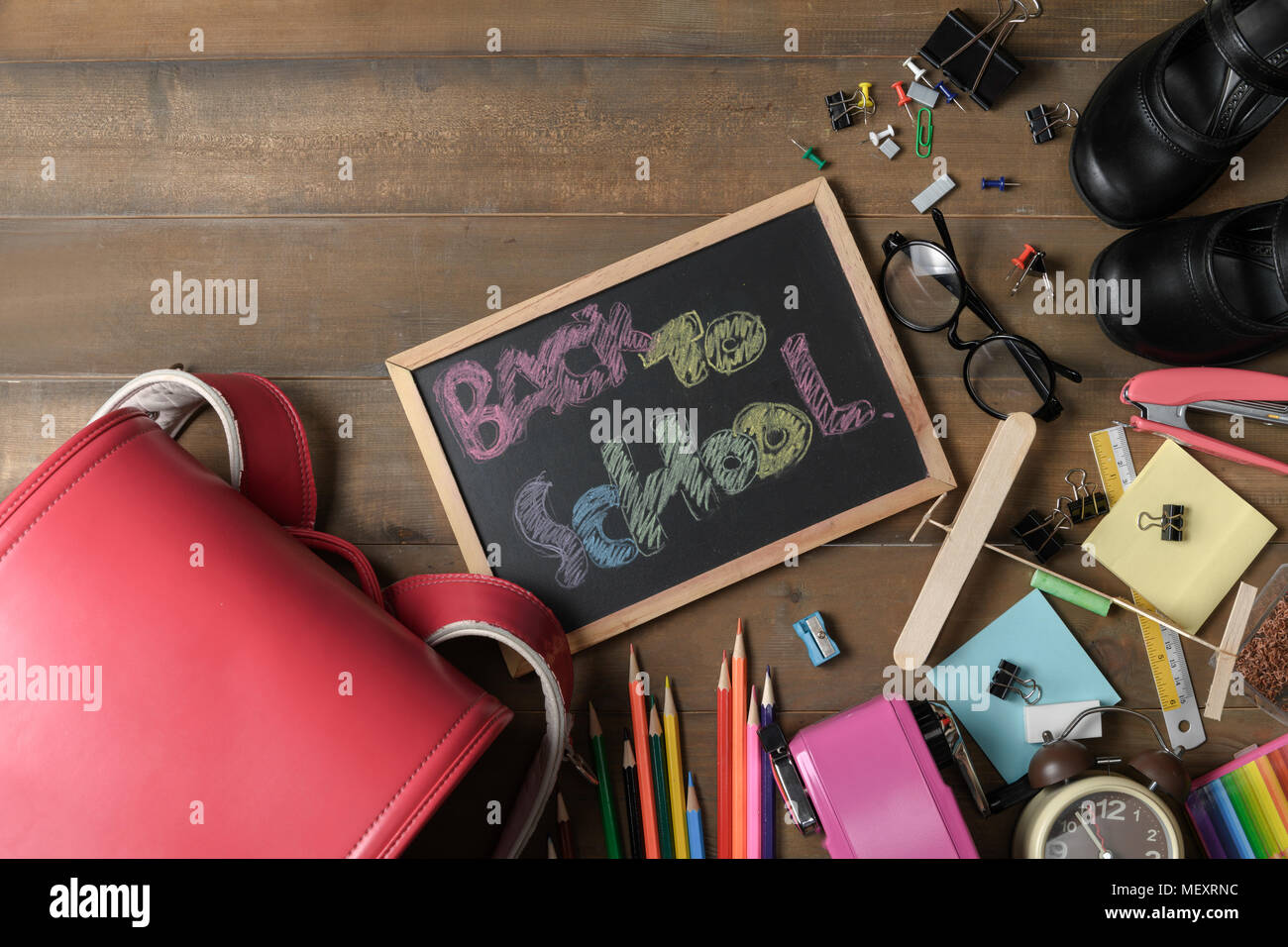 back to school text on black chalk board with bag and school supplies ...