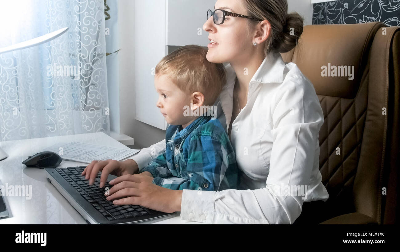 Portrait of young businesswoman looking after her child in office Stock ...