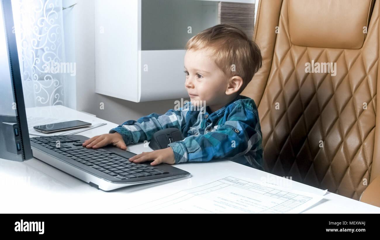Adorable 2 years old toddler boy using computer in office. Concept of ...