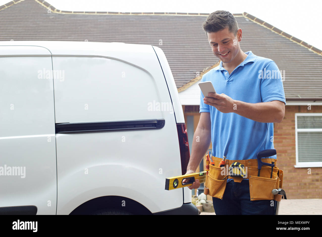 Builder With Van Checking Text Messages On Mobile Phone Outside House ...