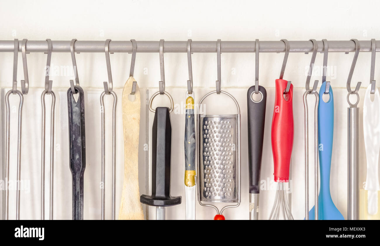 Many different kitchenware hanging on a white kitchen wall Stock Photo ...