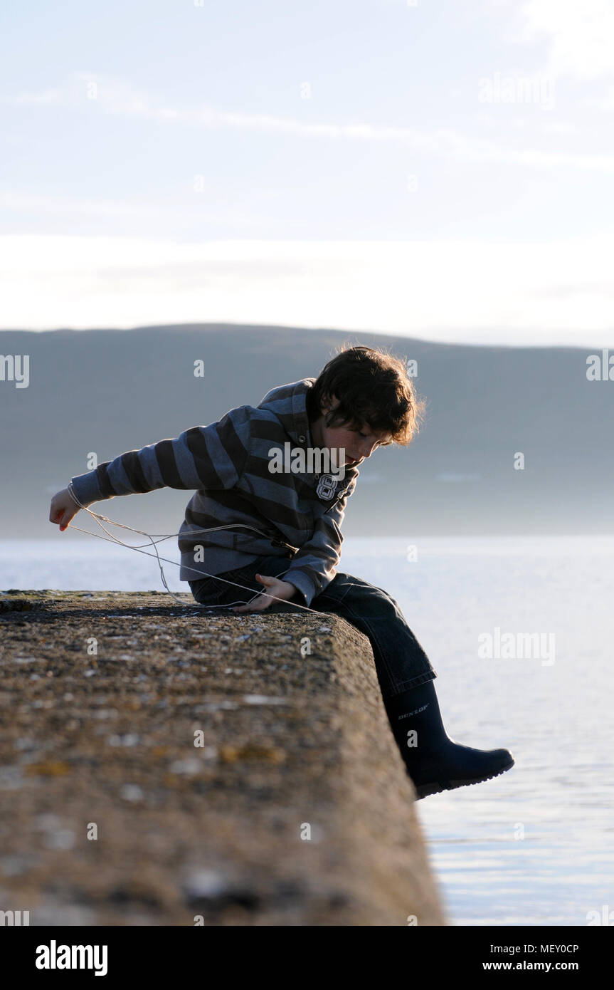 You boy fishing off a pier for crabs or fish Stock Photo - Alamy