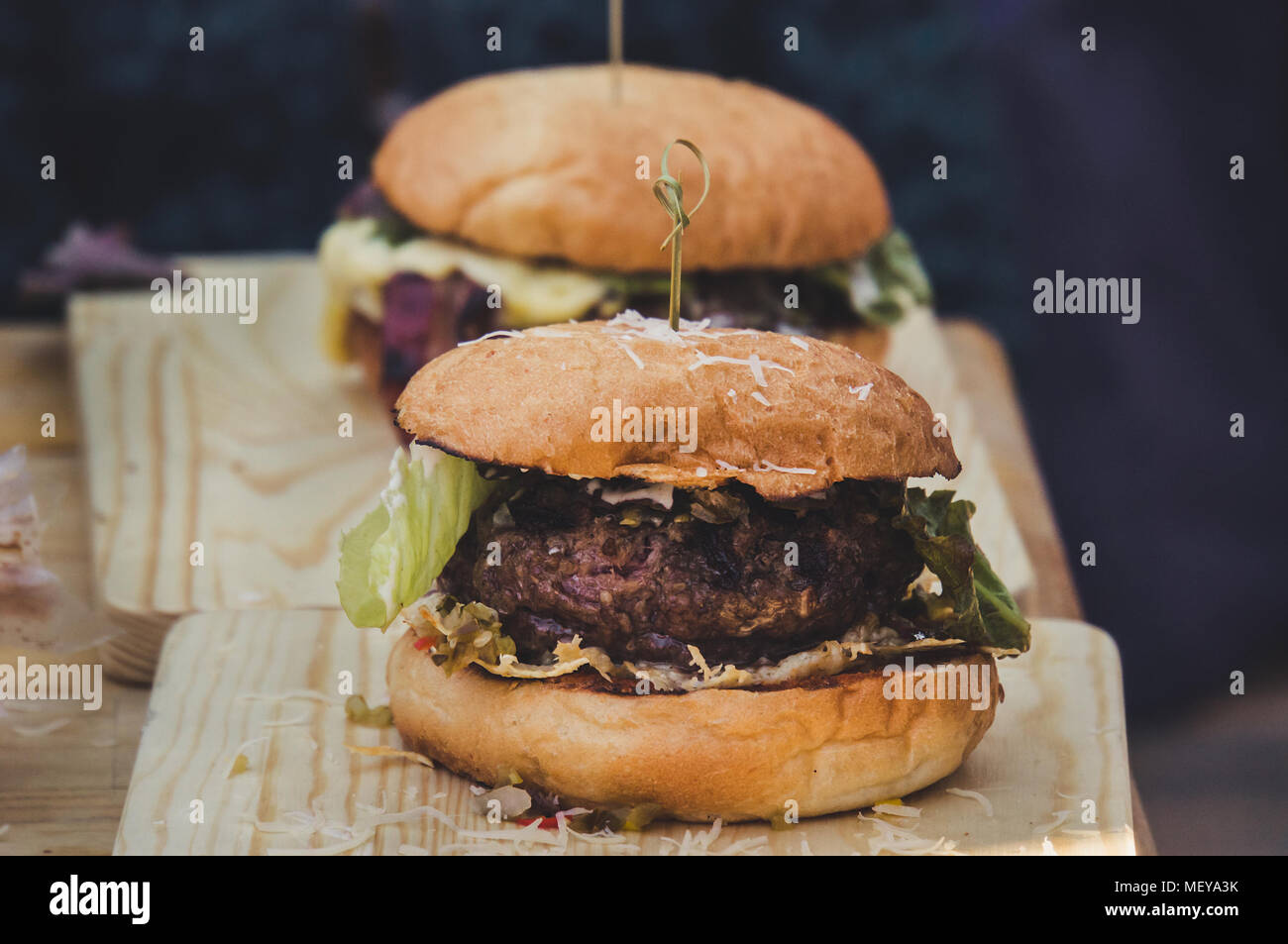 Two craft beef burgers on wooden table isolated on black background ...