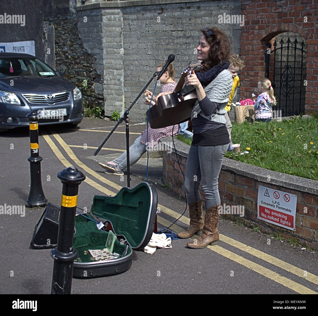 female busker playing a guitar on the street at a local country market ...