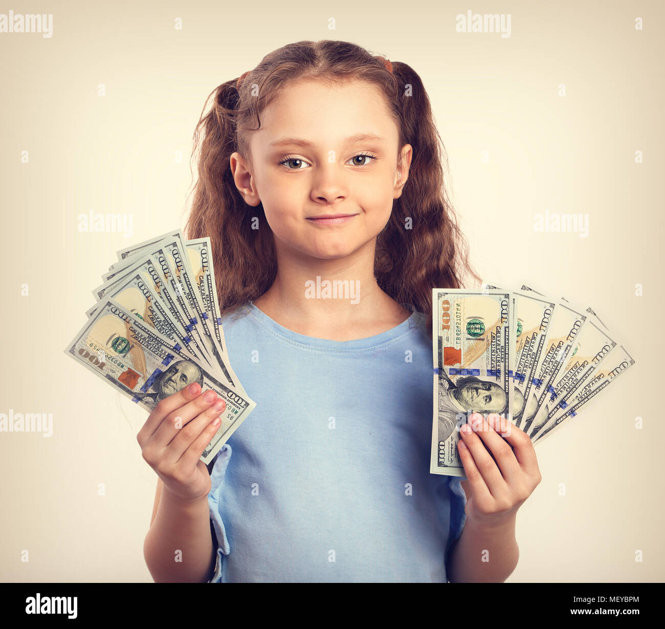 Happy smiling rich kid girl holding money in two hands with calm ...
